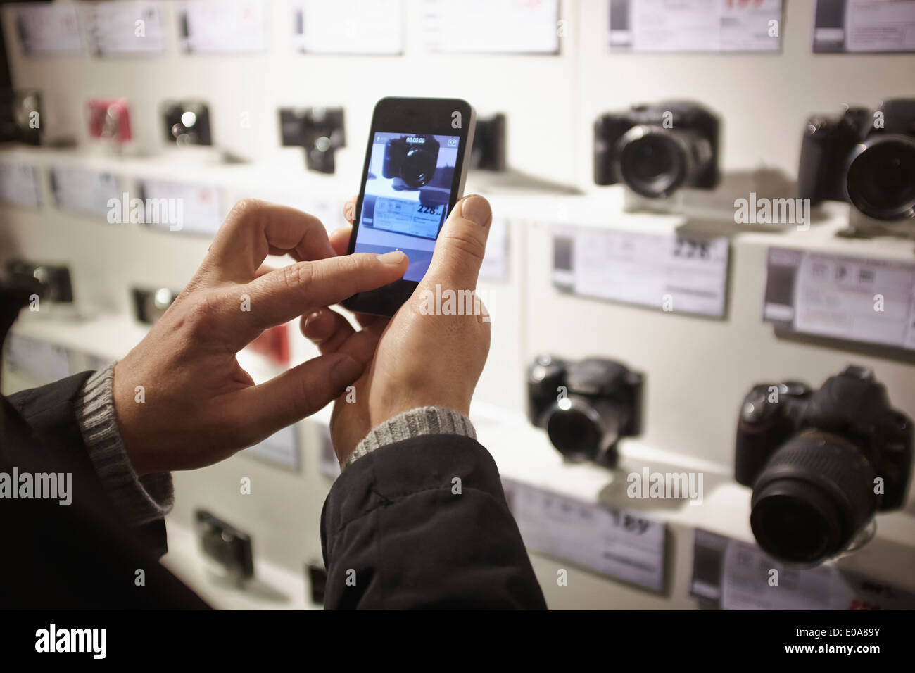 Mid adult man photographing camera's in shop display using smartphone ...