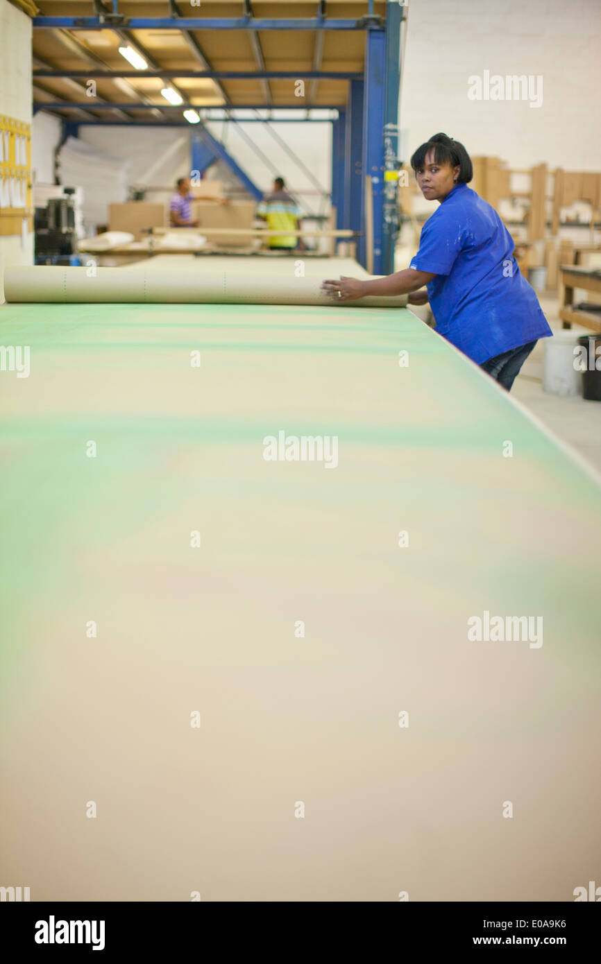 Upholsterer unrolling a length of textile on workbench Stock Photo - Alamy