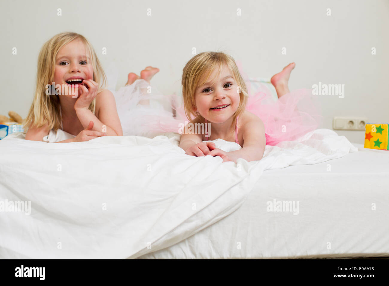 Portrait of two young sisters lying on bed Stock Photo - Alamy