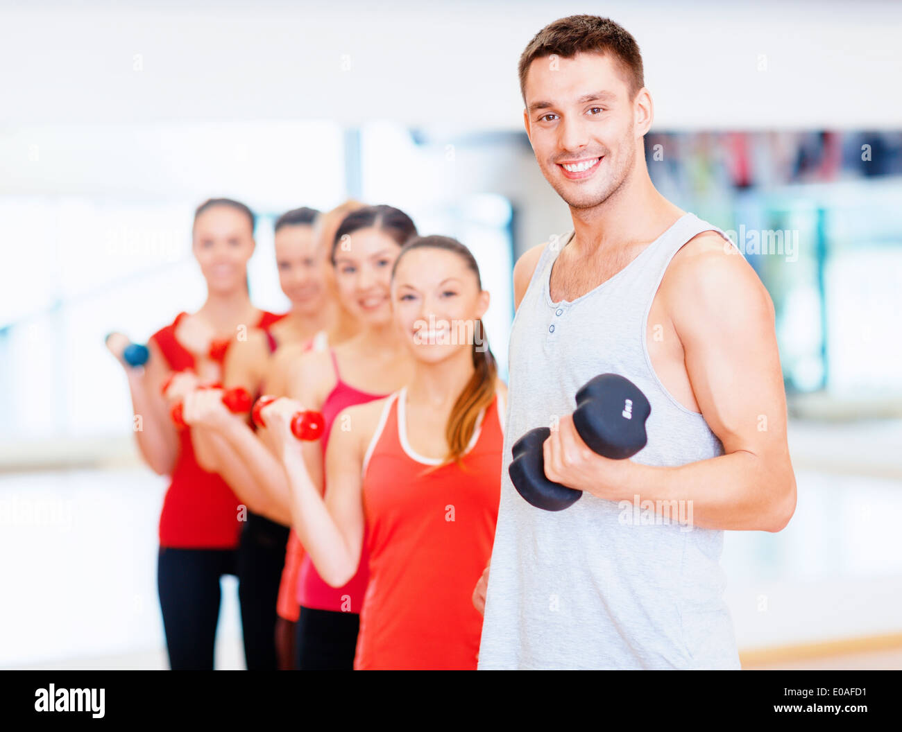 group of smiling people with dumbbells in the gym Stock Photo - Alamy