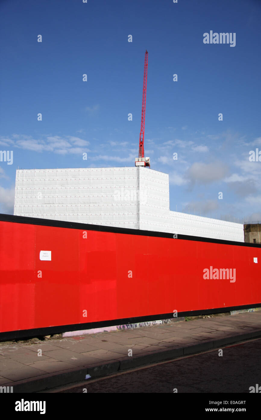 white wrapped building with red and black wall to the front, blue sky ...