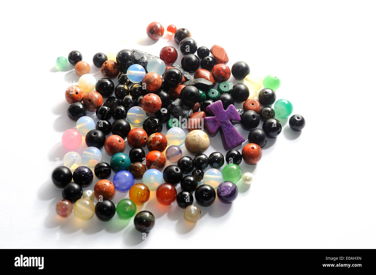 Mix of colorful polished gemstones balls and a cross on the white ...