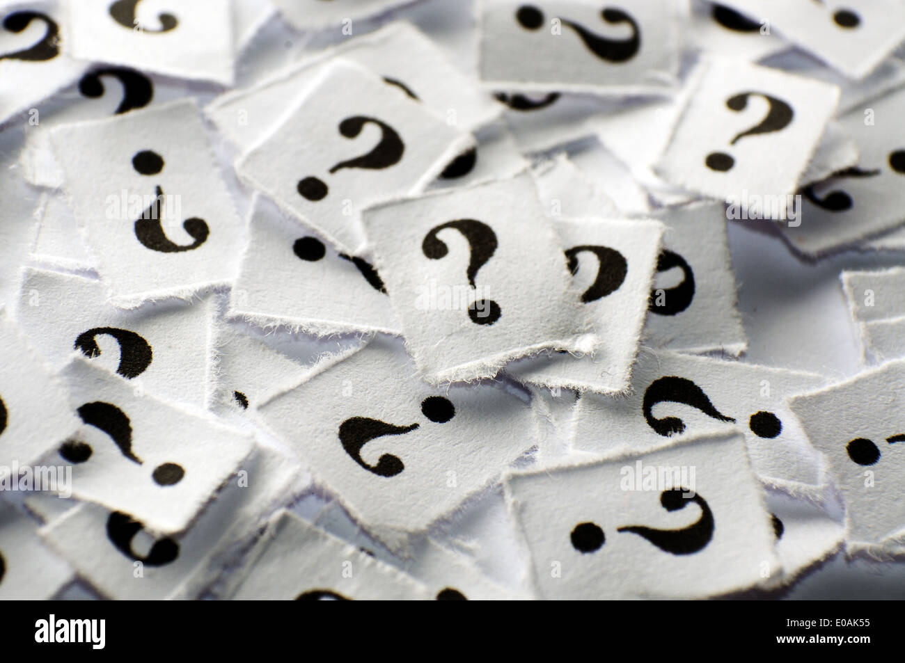 lot of question marks on white papers -hard light Stock Photo - Alamy