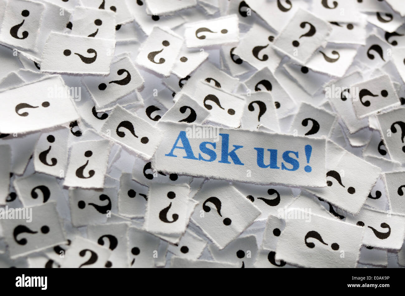 ask us question marks on white papers -hard light Stock Photo - Alamy