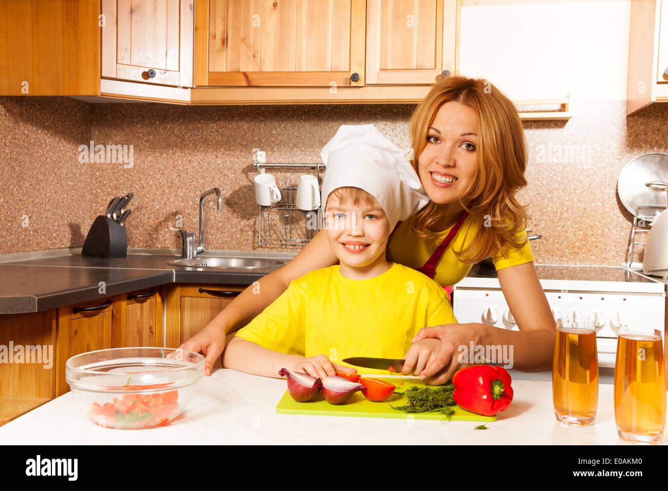 Happy boy using toque cuts vegetables with mother Stock Photo - Alamy