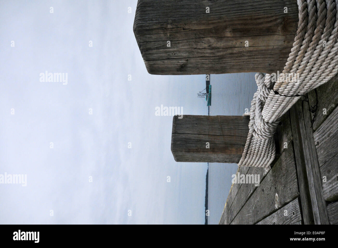 Rope wrapped around posts on dock with ship in distance Stock Photo - Alamy