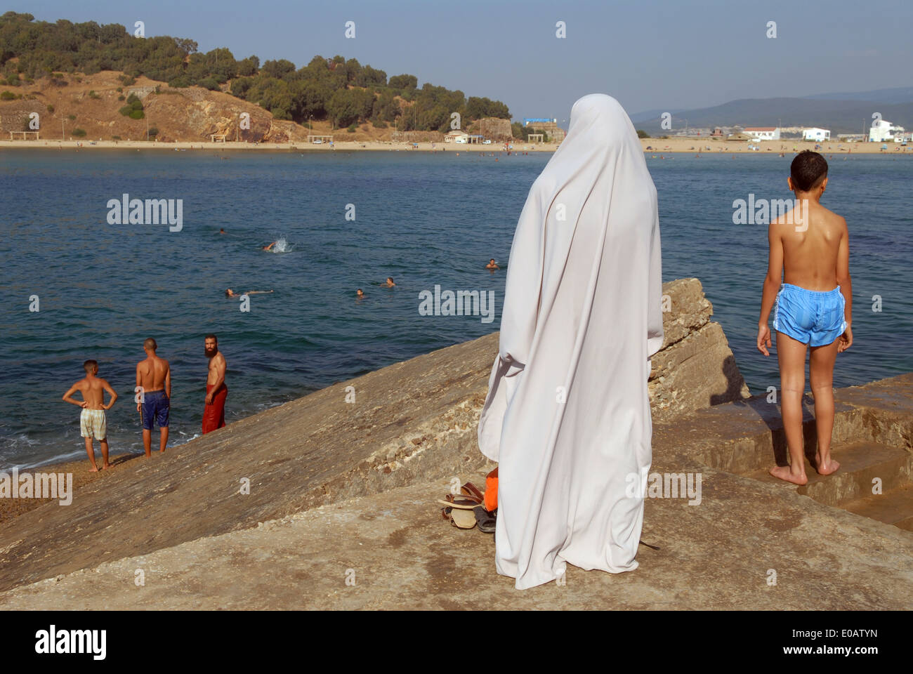 Tunisia, bathing young people and veiled woman on waterfront of Tabarka ...