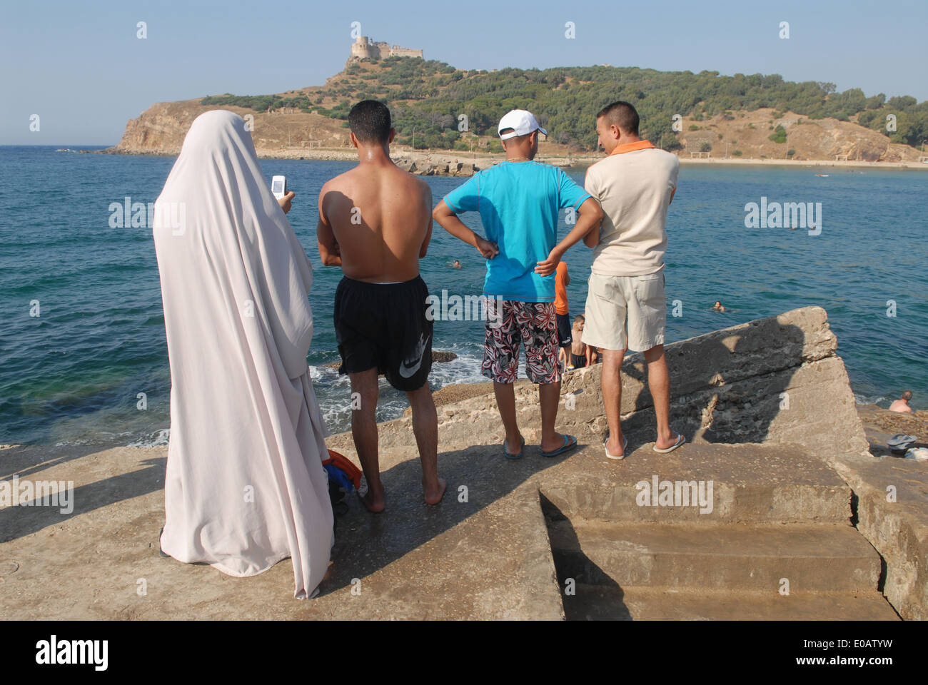 Tunisia, bathing young people and veiled woman on waterfront of Tabarka ...
