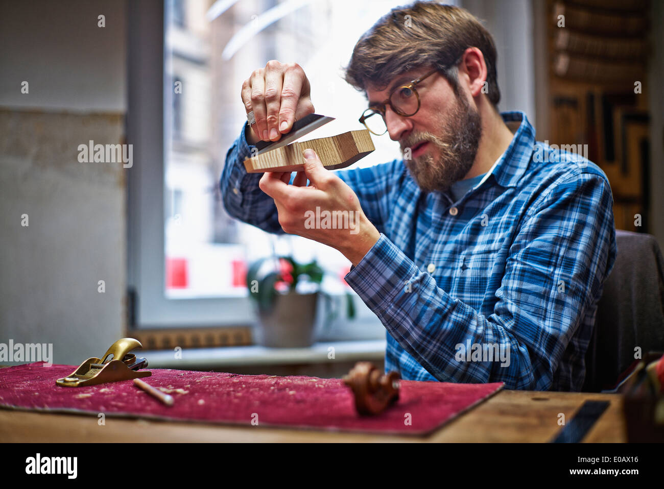 Violin maker in his workshop examining neck of an instrument Stock ...