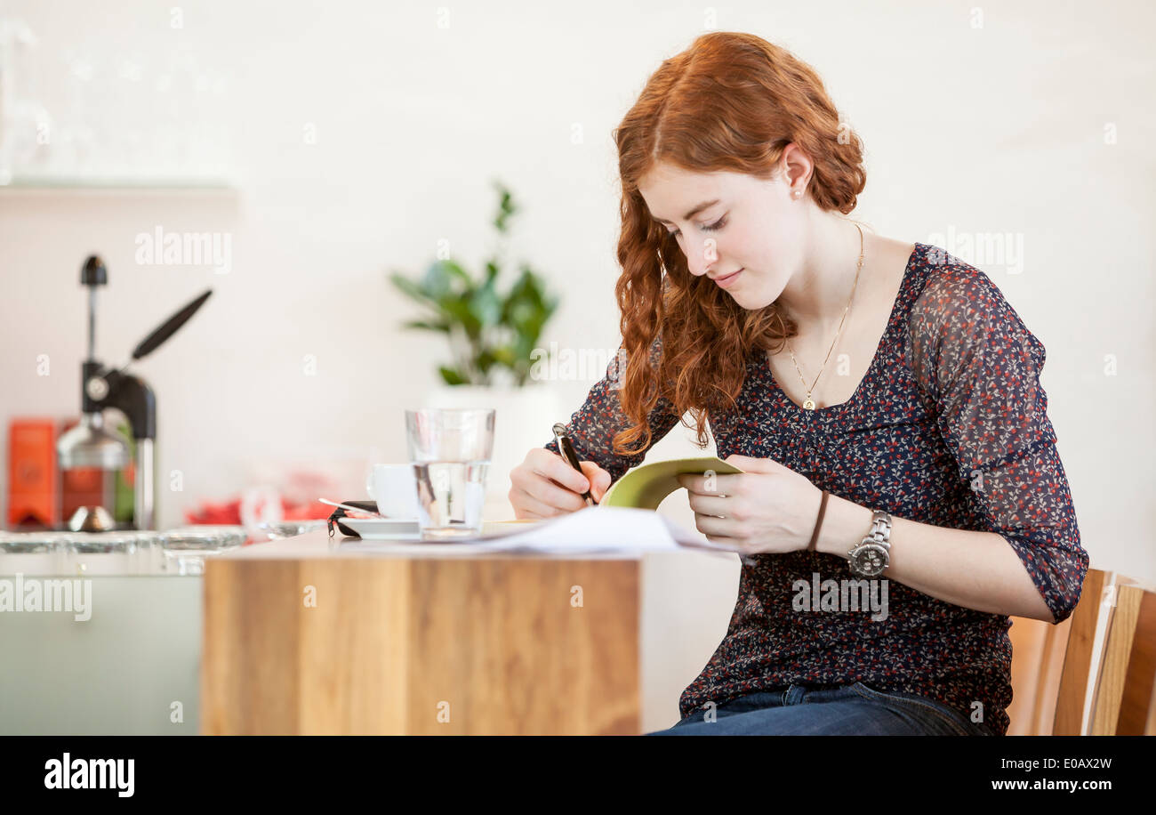 Young woman with note-book writing in cafe Stock Photo - Alamy