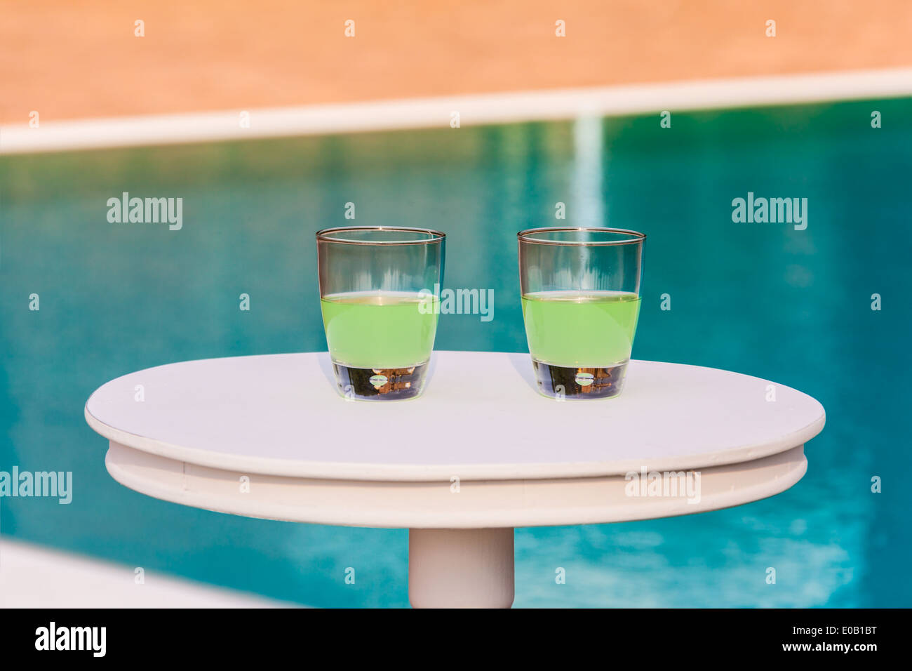 two drinks on a white table with a swimming pool as background Stock ...