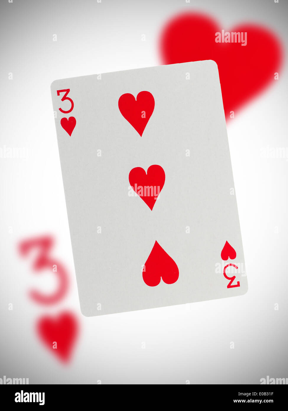 Playing card with a blurry background three of hearts Stock Photo - Alamy