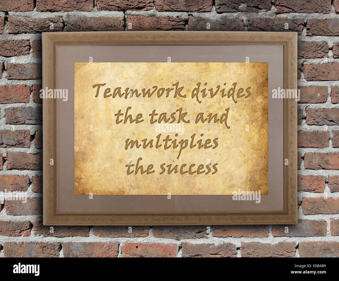 Old wooden frame with written text on an old wall - Teamwork divides ...