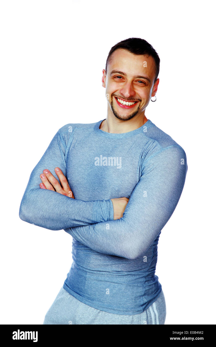 Portrait of a smiling sportsman with arms folded over white background ...