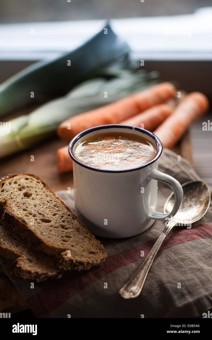 Homemade chicken broth in cup with slices of bread and ingredients ...