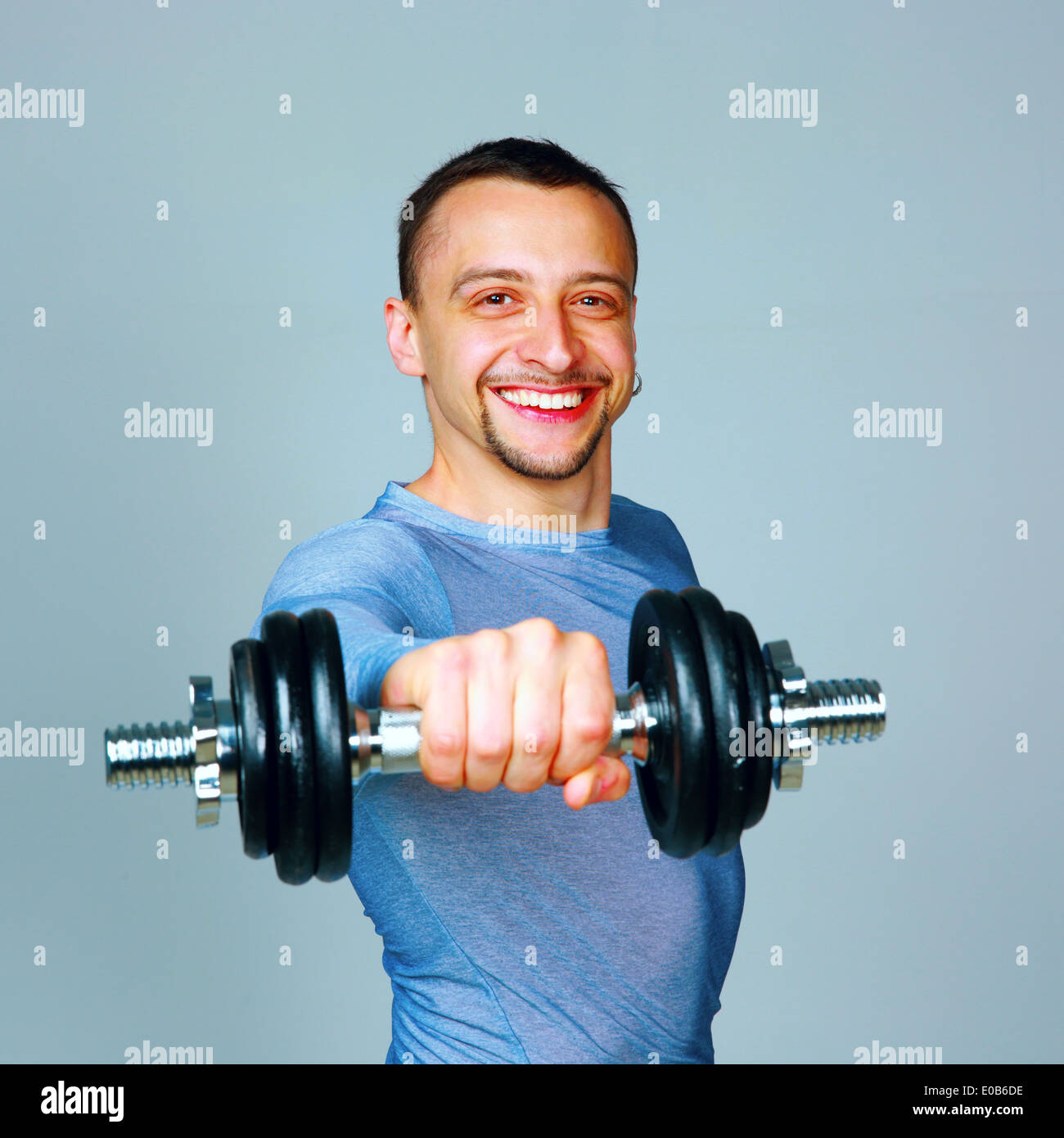 Happy man working out with dumbbells over gray background Stock Photo ...