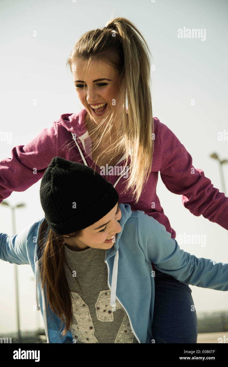Happy young woman carrying friend piggyback Stock Photo - Alamy