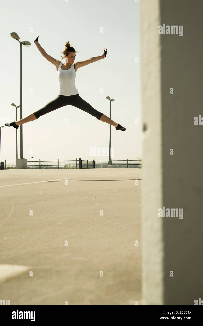 Young woman jumping mid-air on parking level Stock Photo - Alamy