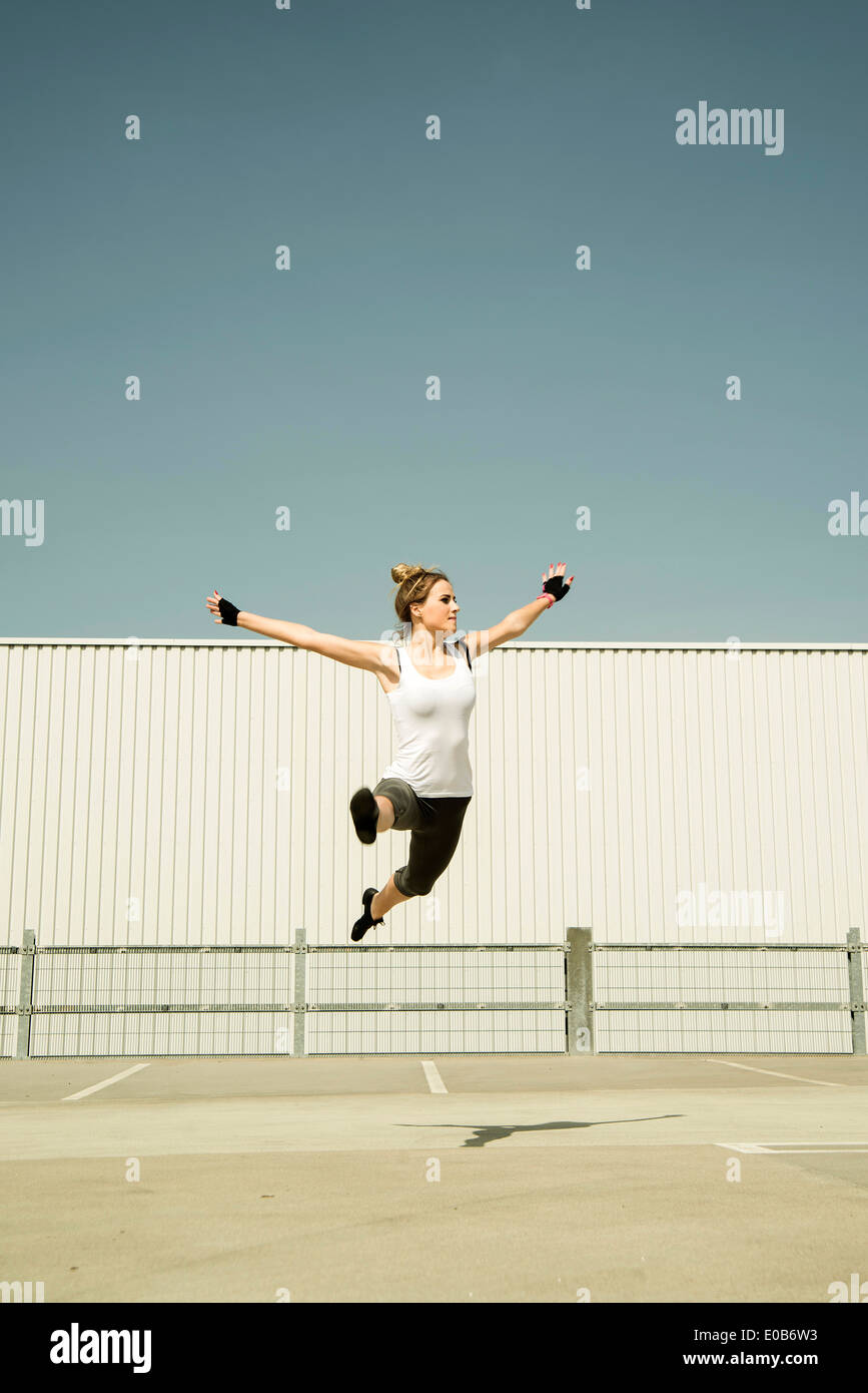 Young woman jumping mid-air on parking level Stock Photo - Alamy