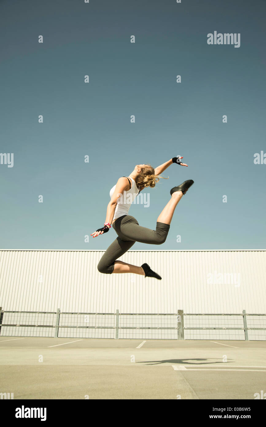 Young woman jumping mid-air on parking level Stock Photo - Alamy