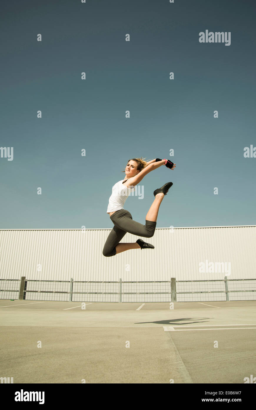 Young woman jumping mid-air on parking level Stock Photo - Alamy