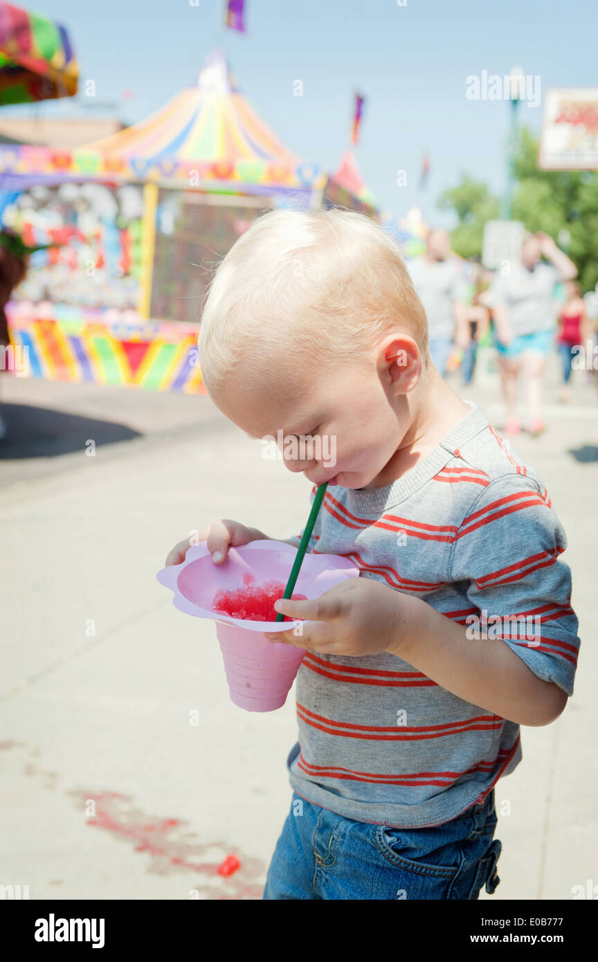 Male toddler concentrating on juice drink at funfair Stock Photo - Alamy