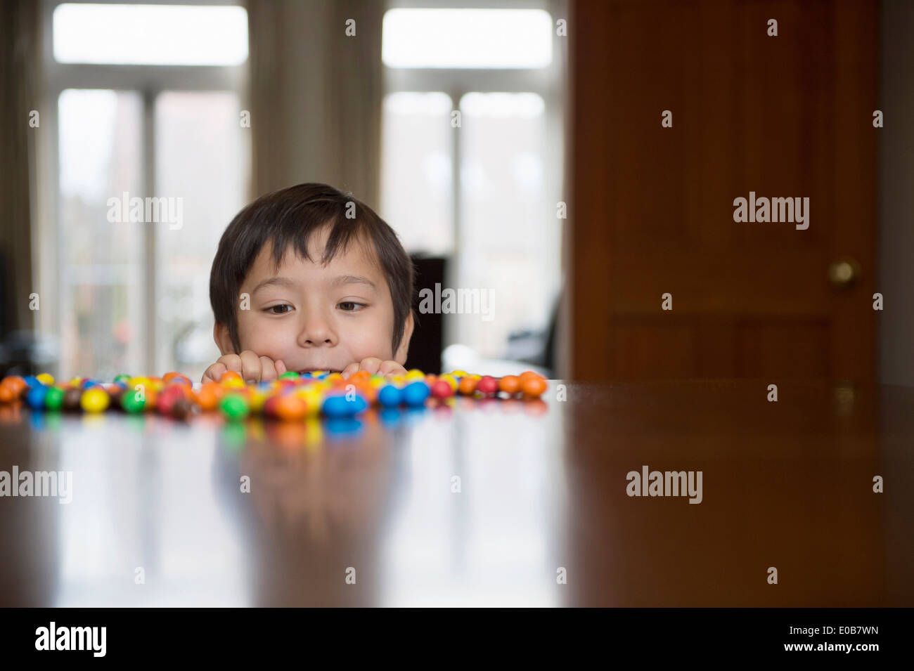 Boy peering over table at candy Stock Photo - Alamy