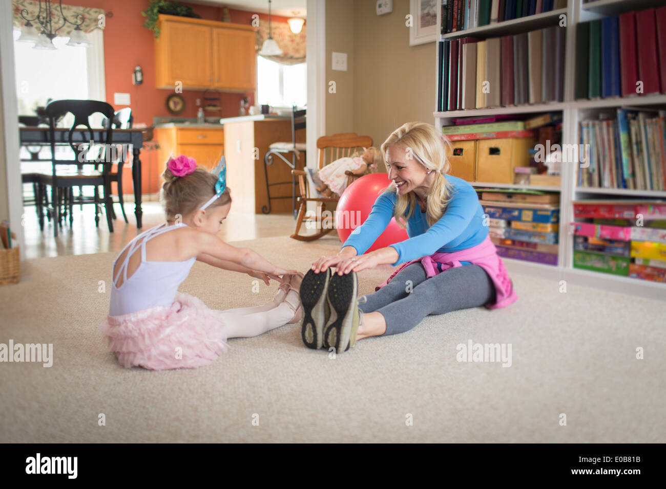 Mother and young daughter warming up for ballet in sitting room Stock ...