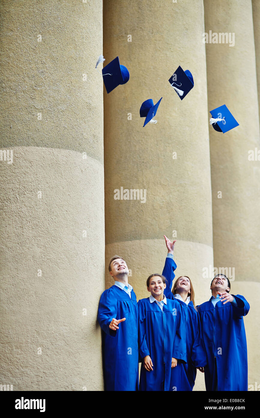 Group of smart students in graduation gowns throwing their hats Stock ...