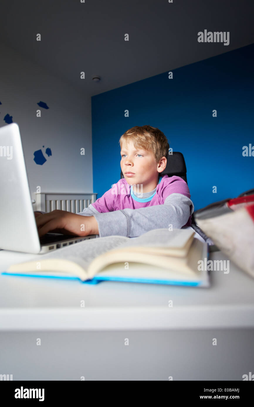 Boy Studying In Bedroom Using Laptop Stock Photo - Alamy