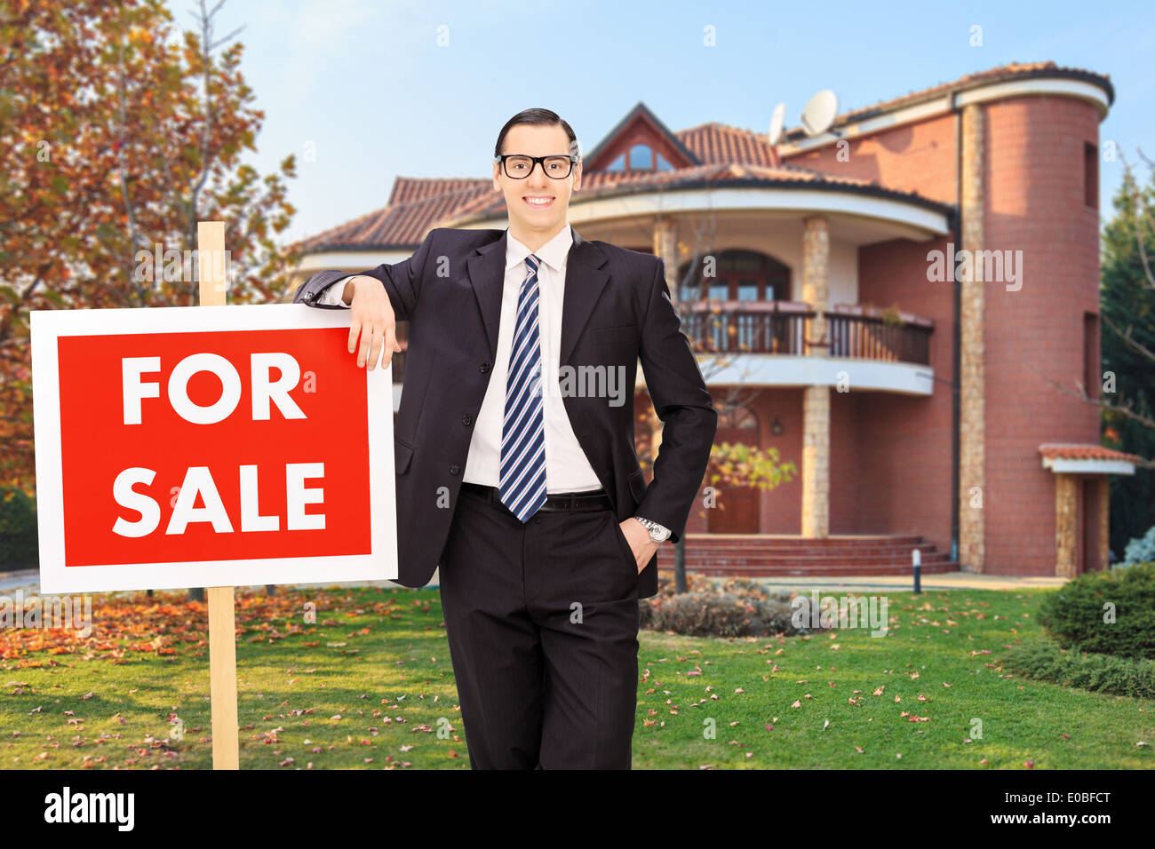 Realtor advertising a house for sale standing in the front yard outside ...
