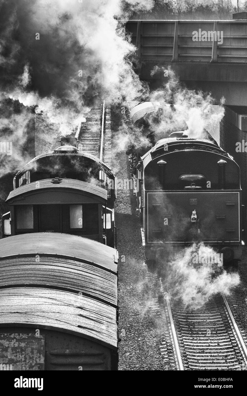 Black and white image looking down onto two steam trains as they pass ...