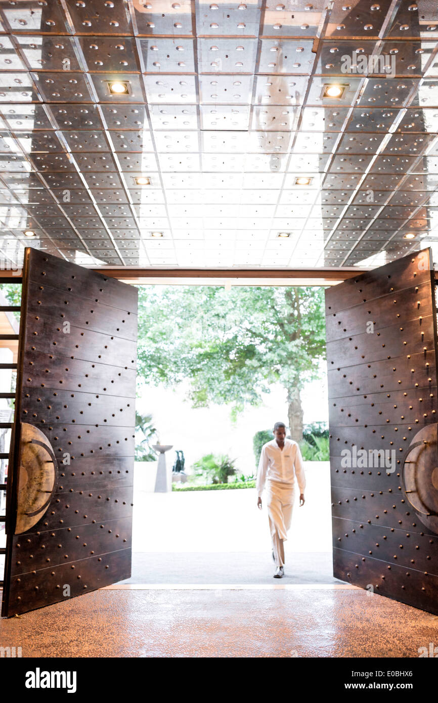 Waiter walking through light filled entrance of gigantic metal doors ...