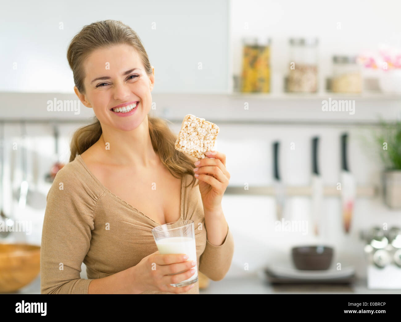 Happy young woman having snacks in kitchen Stock Photo - Alamy