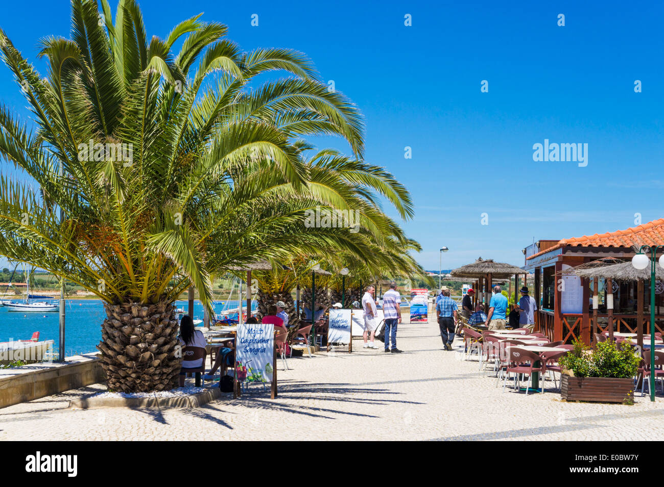 tourists walking along the seafront in the village of Alvor Algarve ...