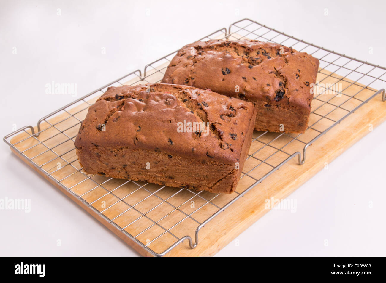 2 Fruit loaves cooling on a wire cooling rack set on a wooden board ( 5 ...