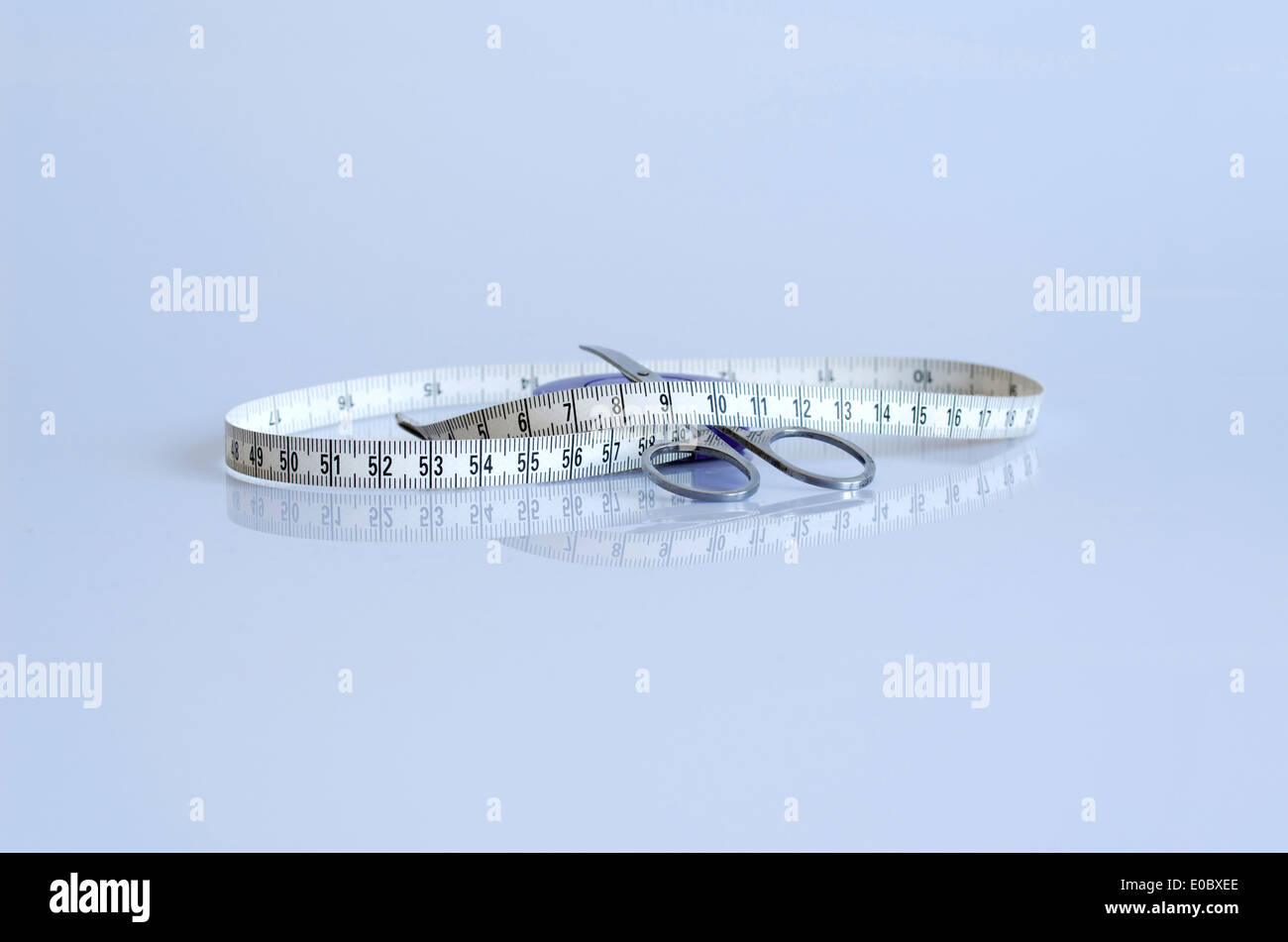 Scissors cutting a measuring tape over white background Stock Photo - Alamy