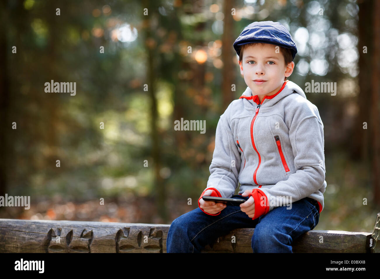 Portrait of little boy sitting on a bench outdoors Stock Photo - Alamy