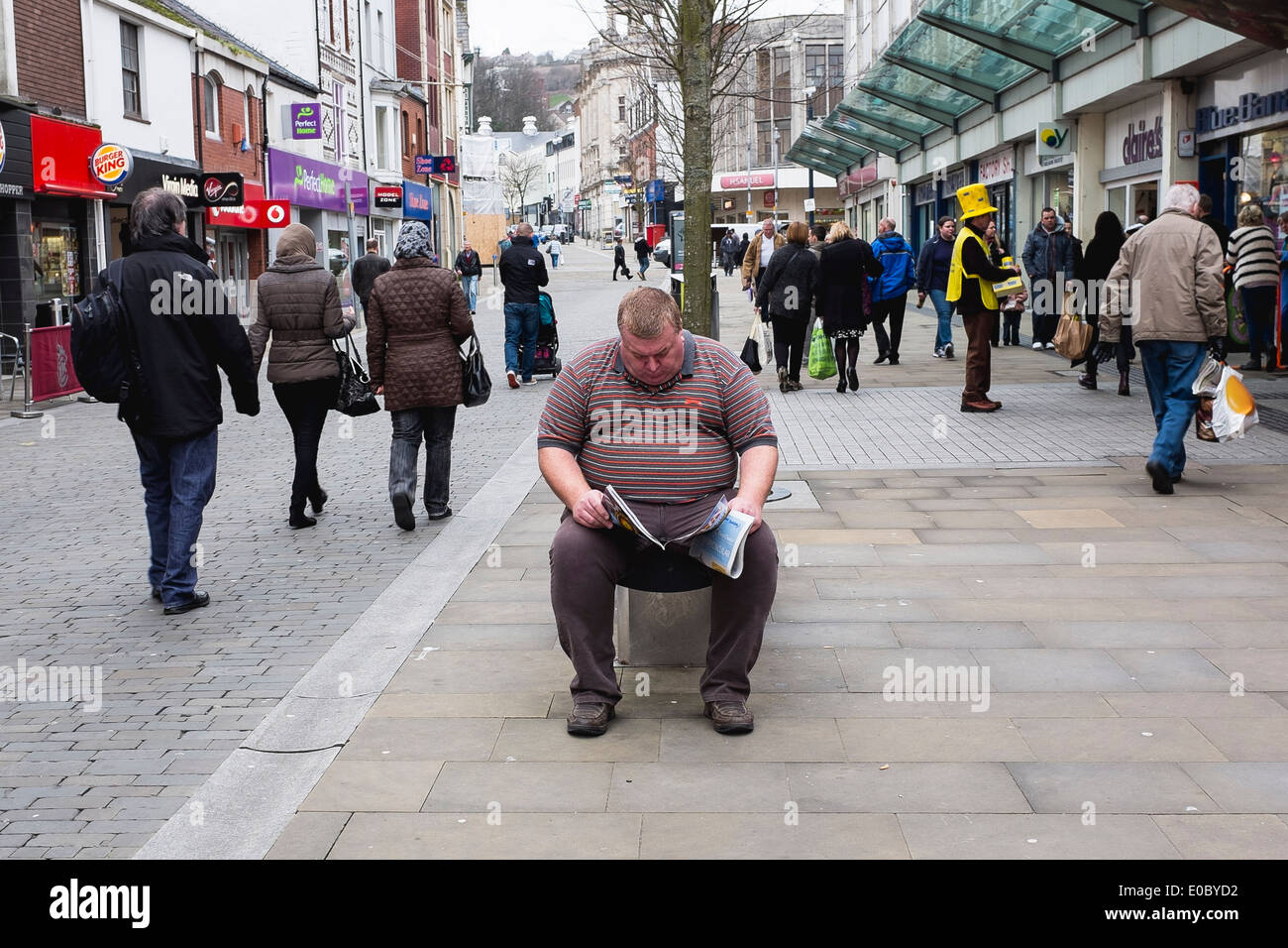 Man reading a paper in a busy shopping street Stock Photo - Alamy