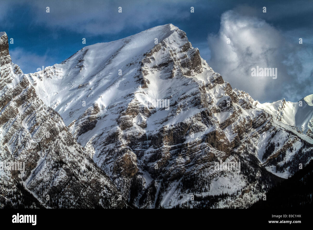 Snow covered, rugged, majestic looking peak of Mt. Kidd, against blue ...