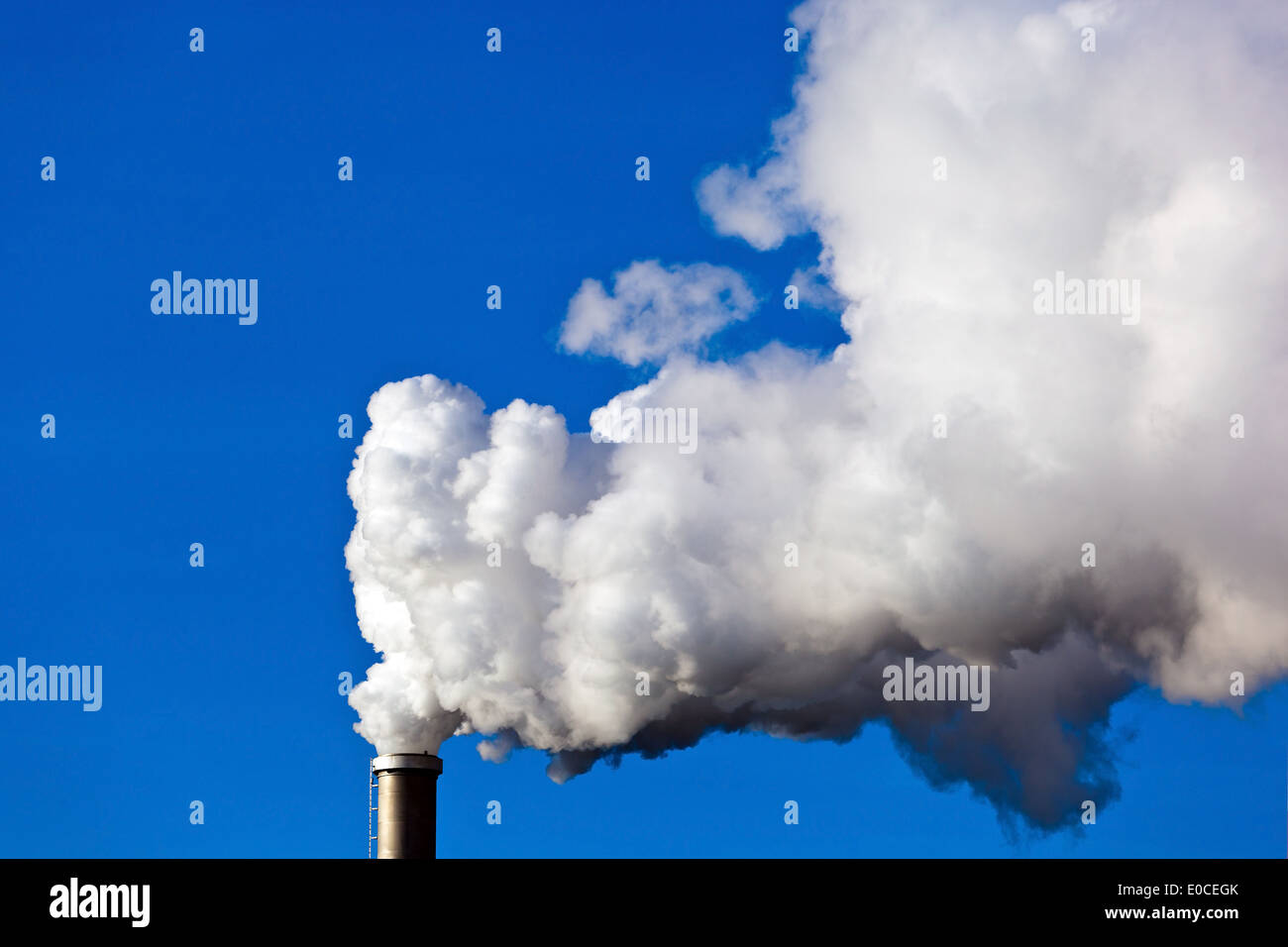 The smoking chimneys of a factory before blue sky. From chimneys white ...