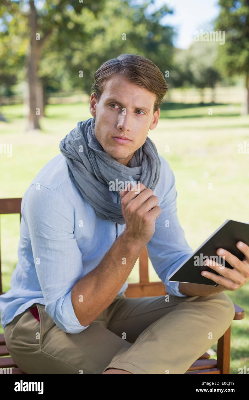 Stylish young man holding notepad and thinking Stock Photo - Alamy