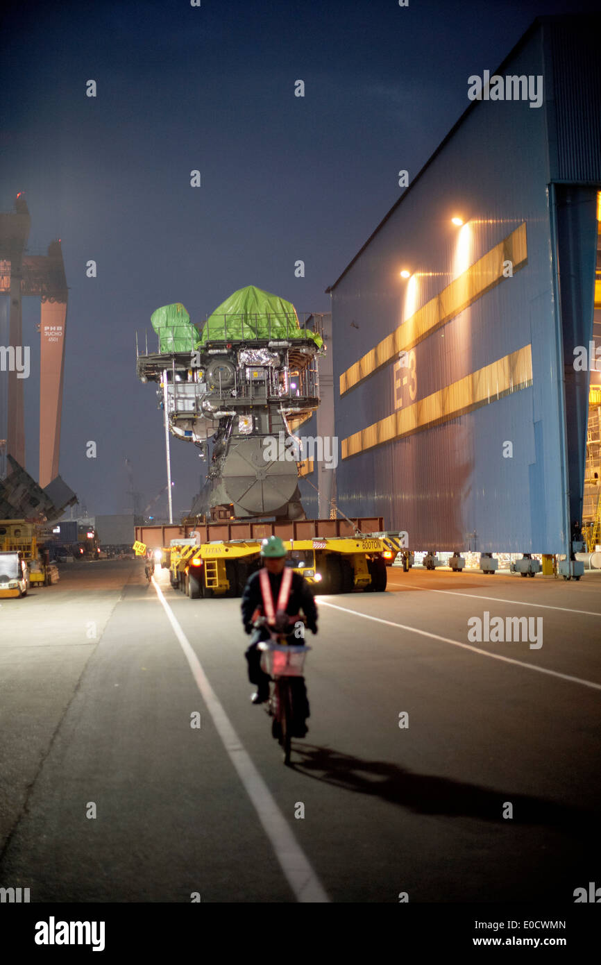 Moped driver leading a giant flatbed truck that is transporting MAN two ...