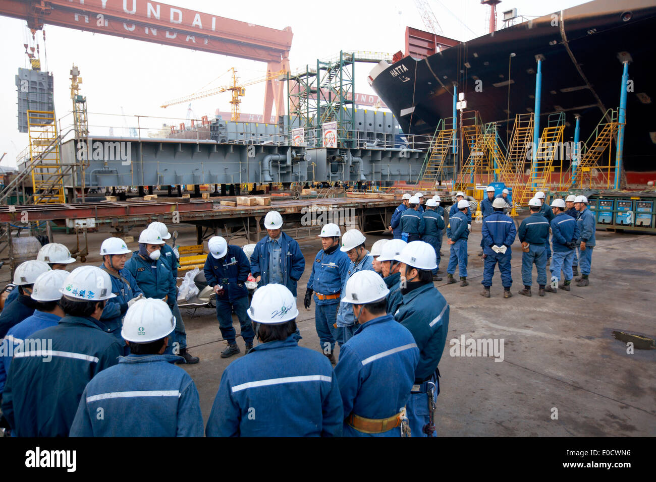 Shipyard workers doing morning exercises before shift, modular ...