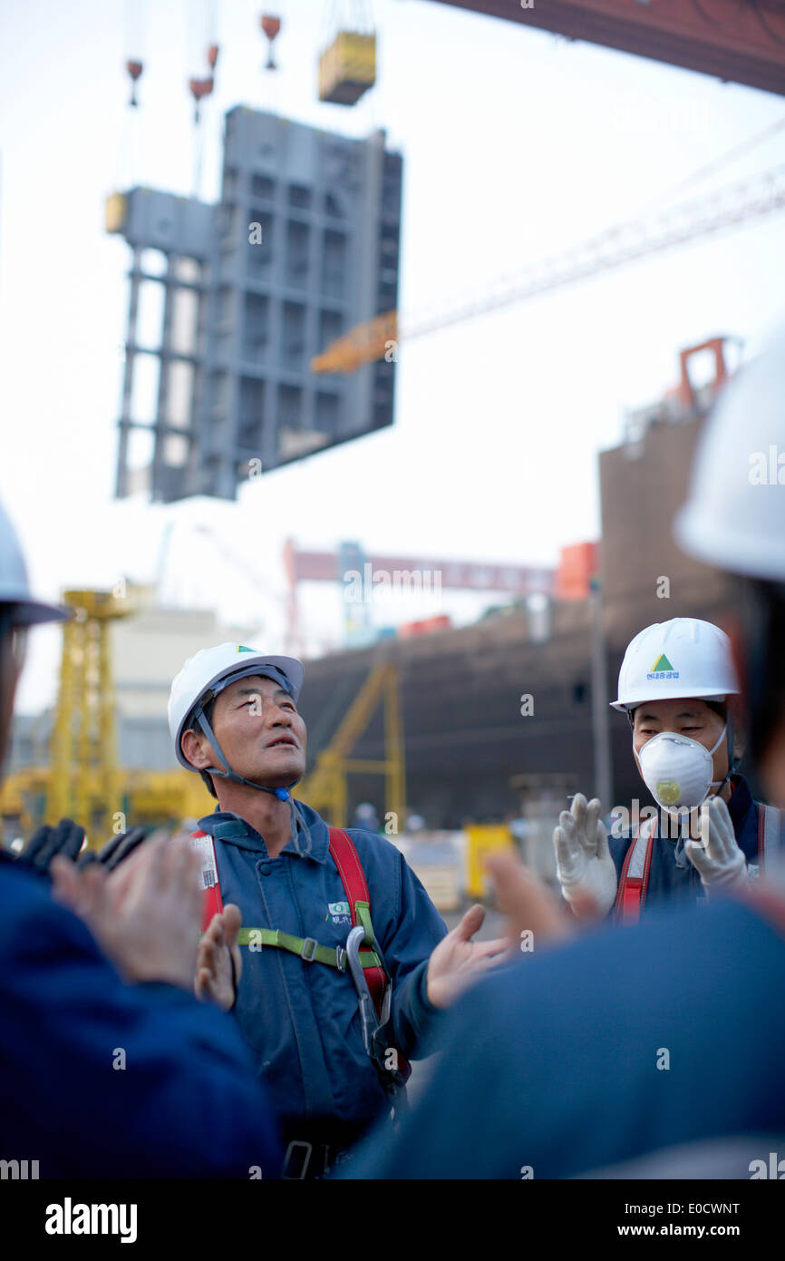 Shipyard workers doing morning exercises before shift, modular ...