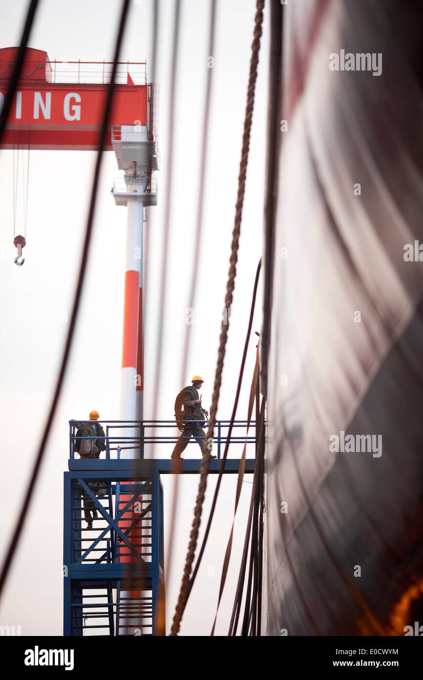 Chinese workers entering a frighter via scaffold steps, Ouhua Shipyard ...
