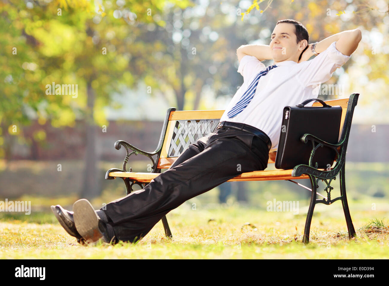 Young businessperson sitting on a bench and relaxing in a park Stock ...