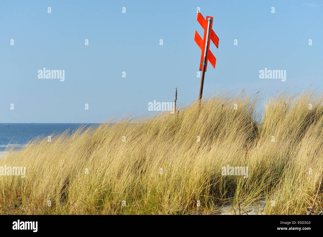 Red double cross in grasses on the top of a dune in front of the North ...