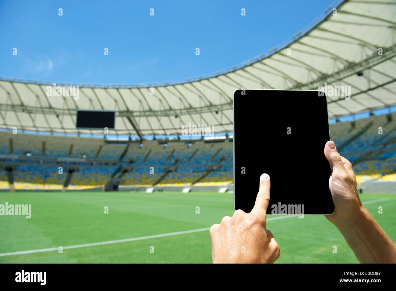 Finger touching blank tablet computer screen in front of soccer field ...