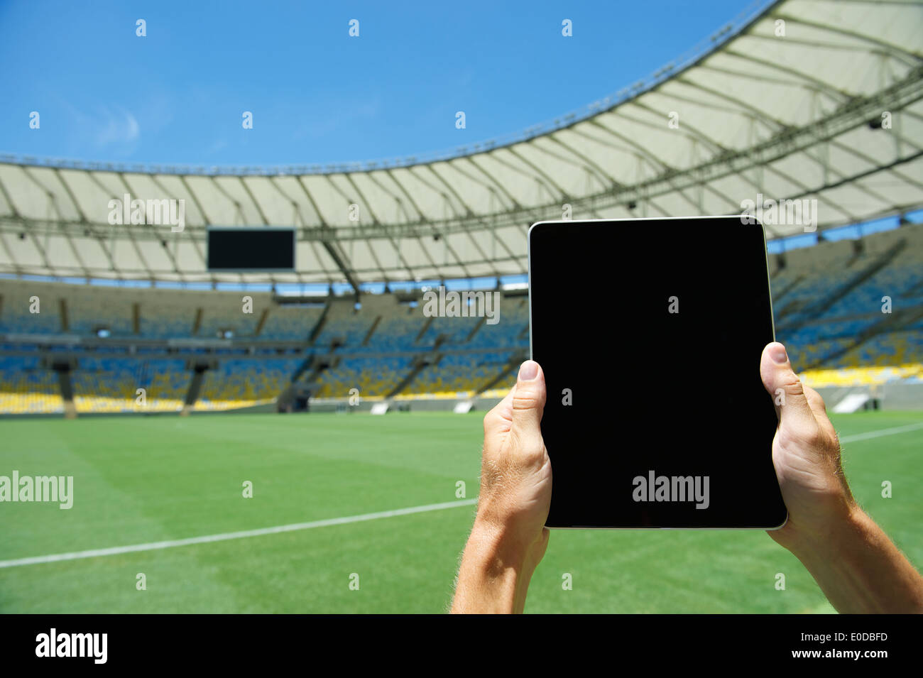 Hands holding blank tablet computer in front of soccer field at ...